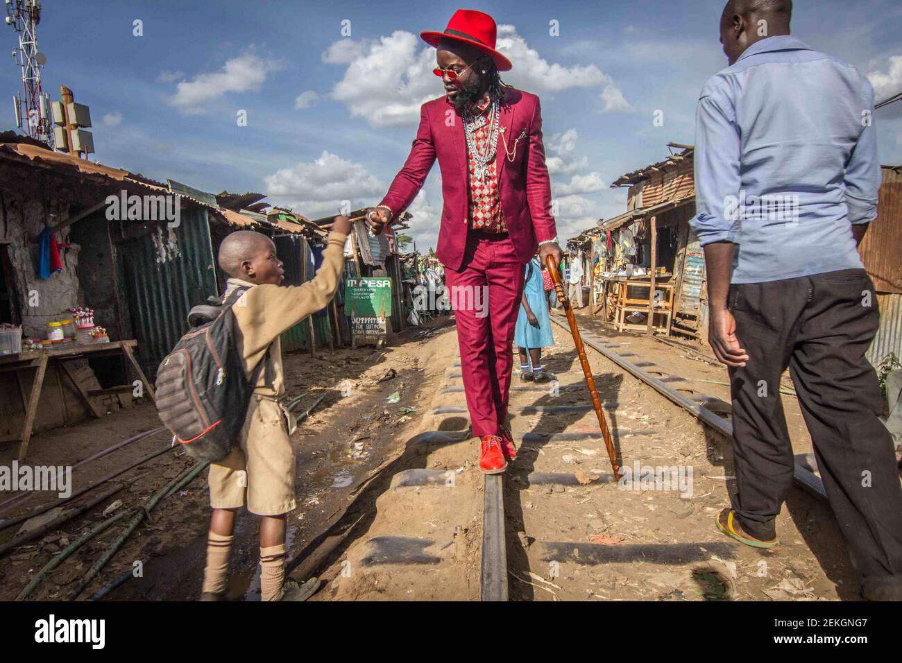 Baqterias walks past the streets of Kibera Slums in his elegant suit ...
