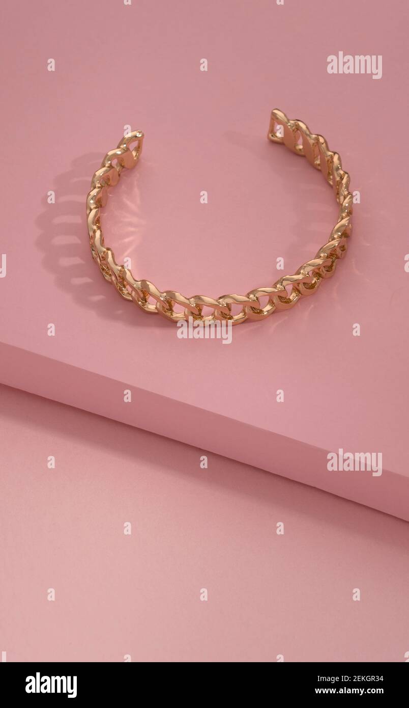 Top view of chain shape golden bracelet on pink background Stock Photo ...