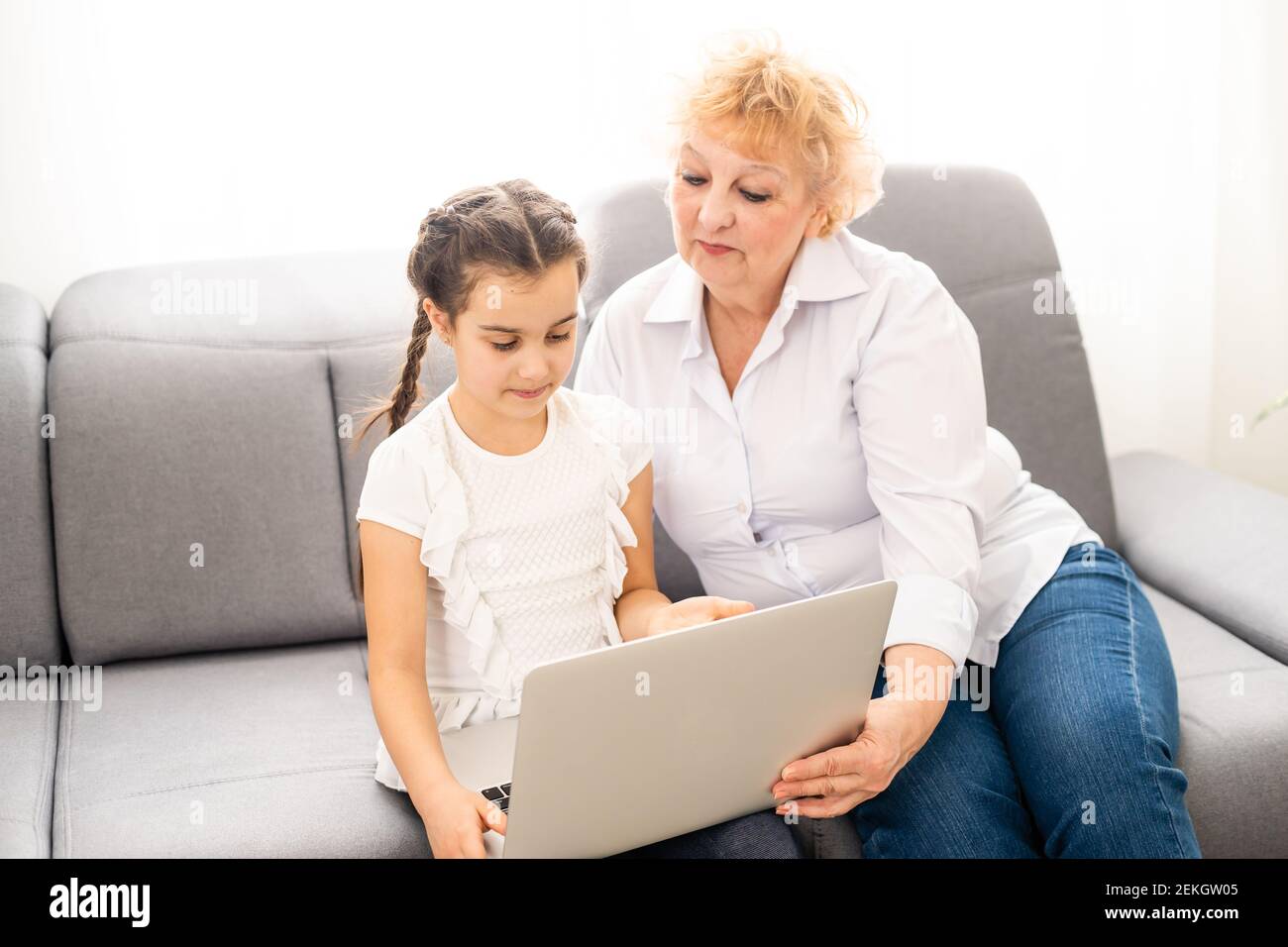 modern grandmother teaching grandchild how to use laptop computer at ...