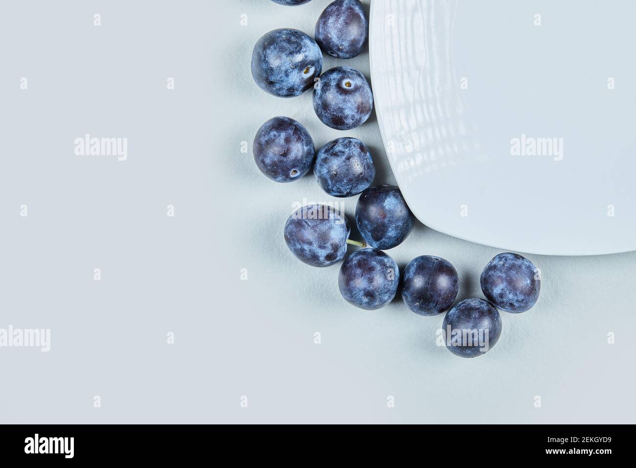 Group of fresh plums on a blue background Stock Photo - Alamy