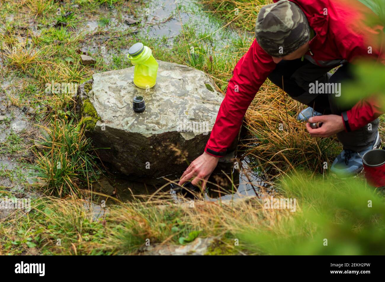 A man in a puddle is taking water. Drink water from a puddle. Draw ...