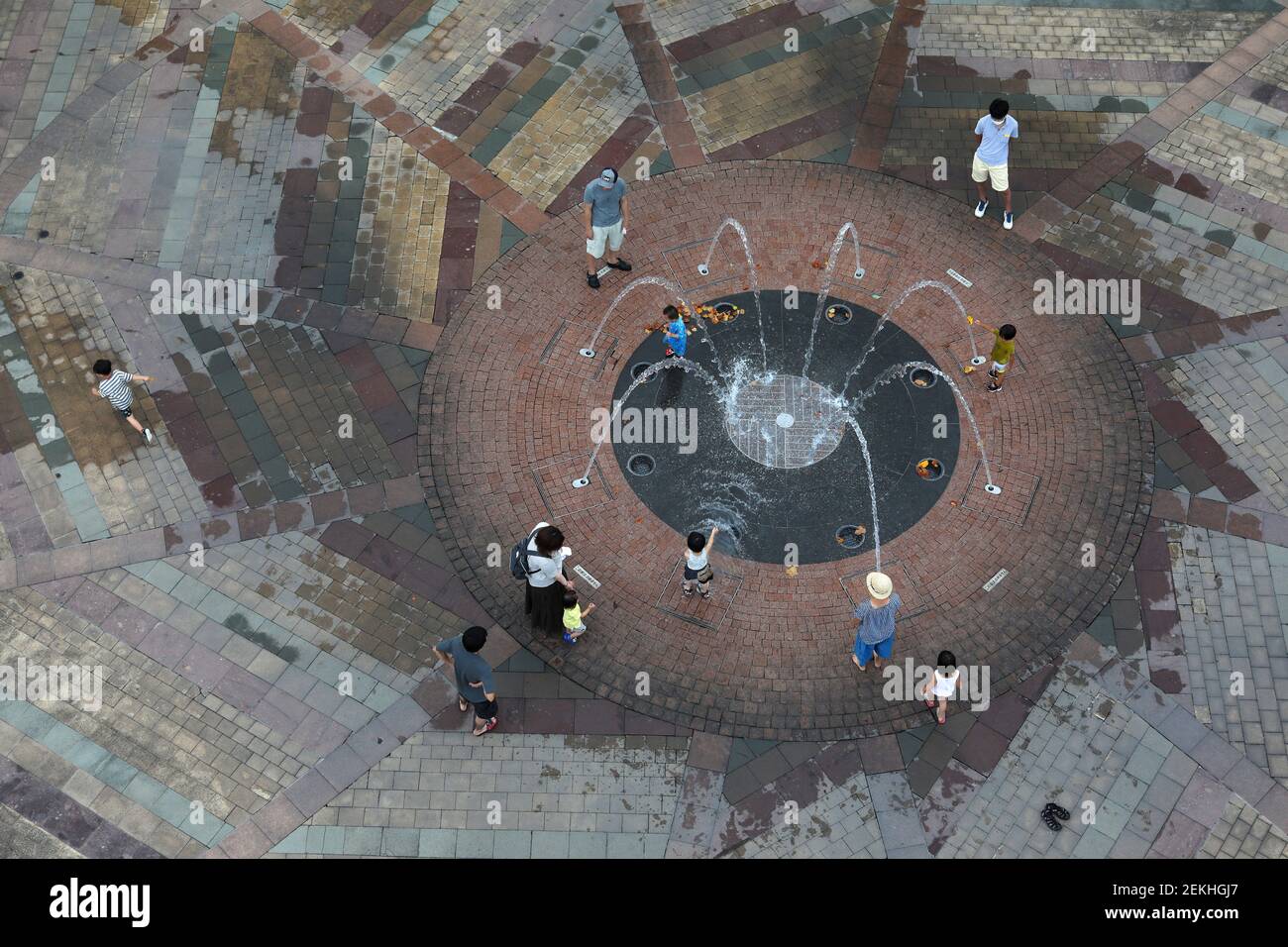 Kids playing around water fountains at the Fugan Canal Kansui Park. The ...