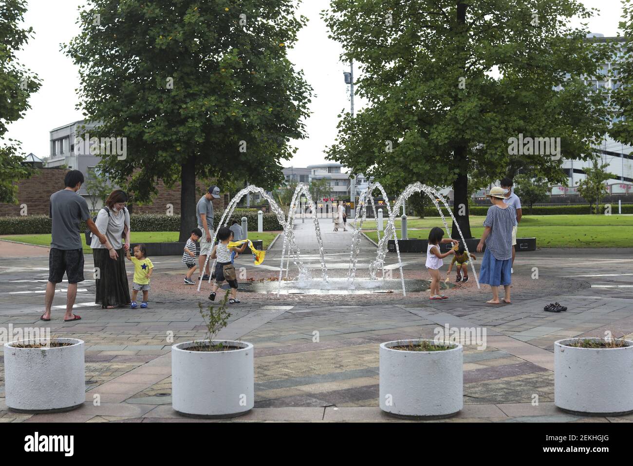 Kids playing around water fountains at the Fugan Canal Kansui Park. The ...