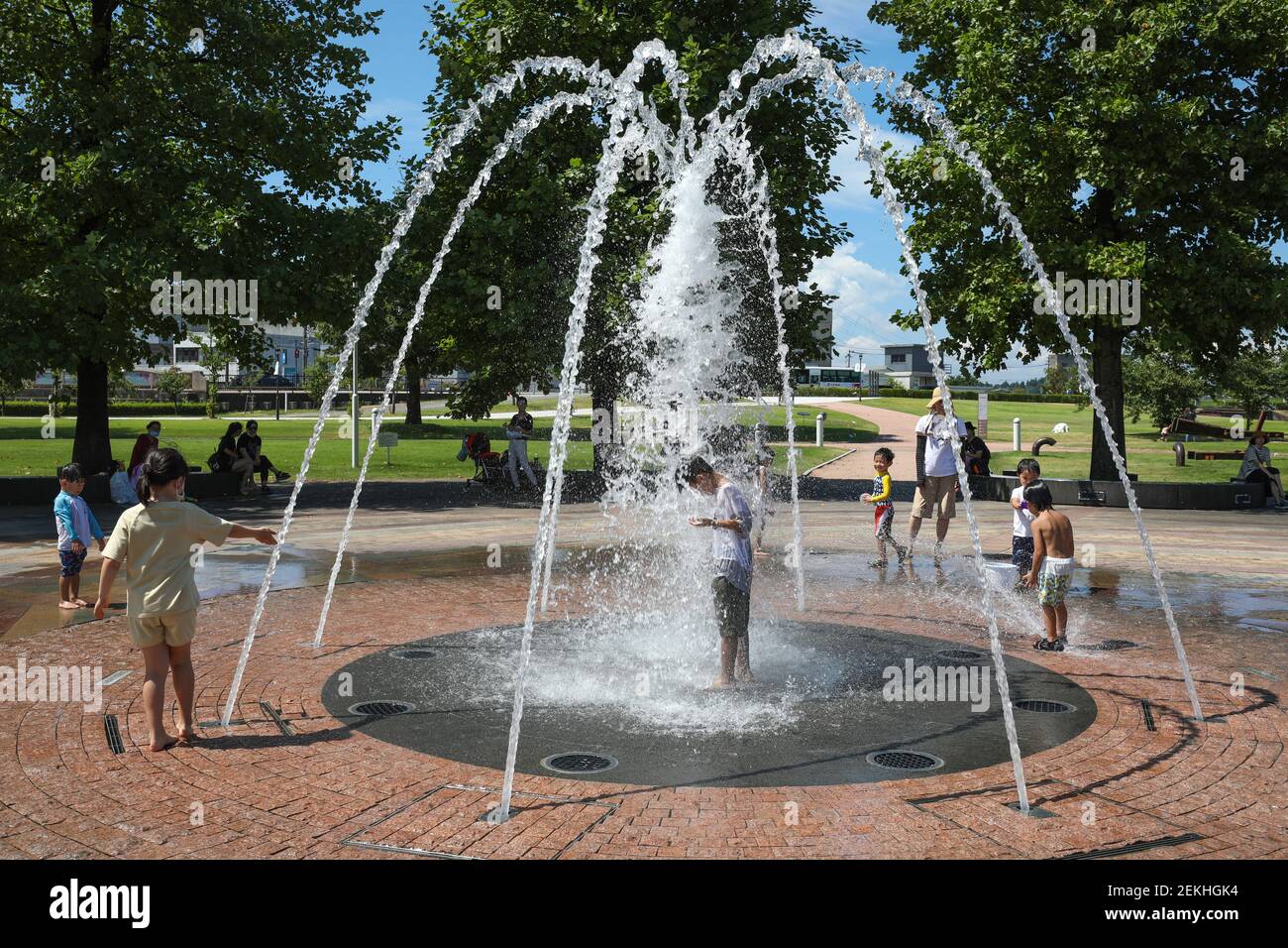 Kids playing around water fountains at the Fugan Canal Kansui Park. The ...