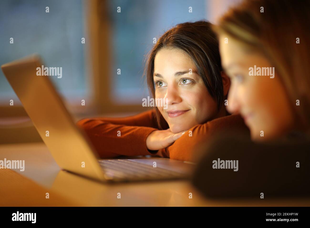 Two friends watching media content on laptop together in the night at ...