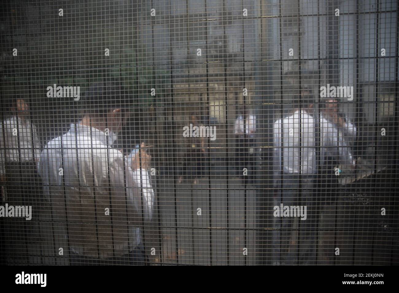 Smokers stand in a circle inside a designated smoker's area while ...