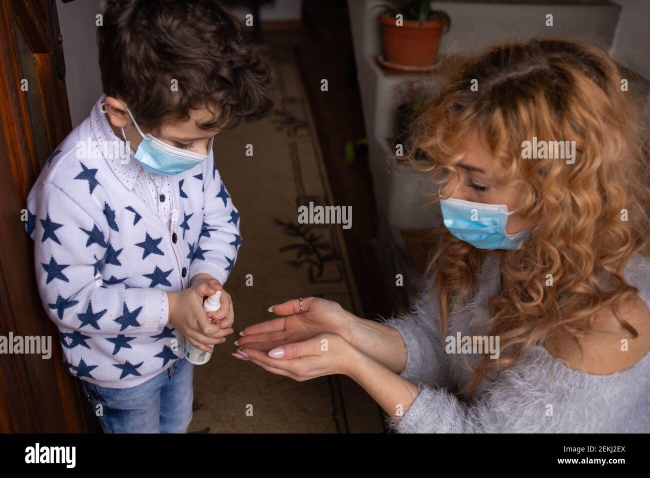 Close-up of childs hands spraying alcohol on his moms hands Stock Photo ...