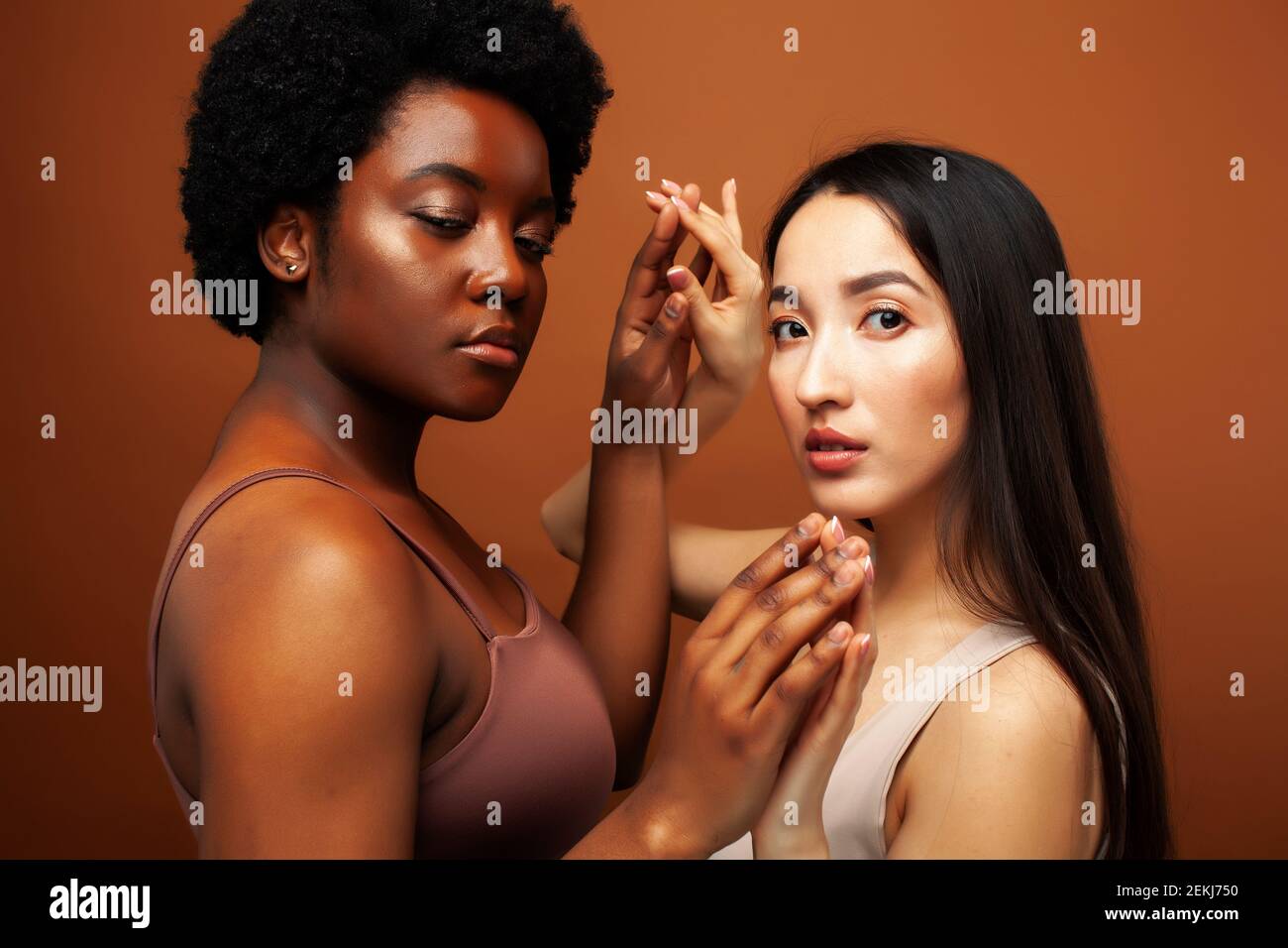 young pretty asian, afro woman posing cheerful together on brown ...