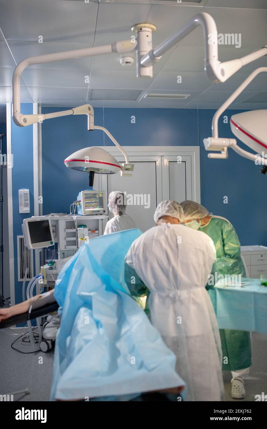 Patient covered with cloth lying on operation table while two ...