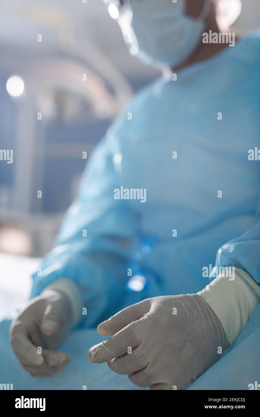 Gloved hands of tired male surgeon sitting in front of camera in ...