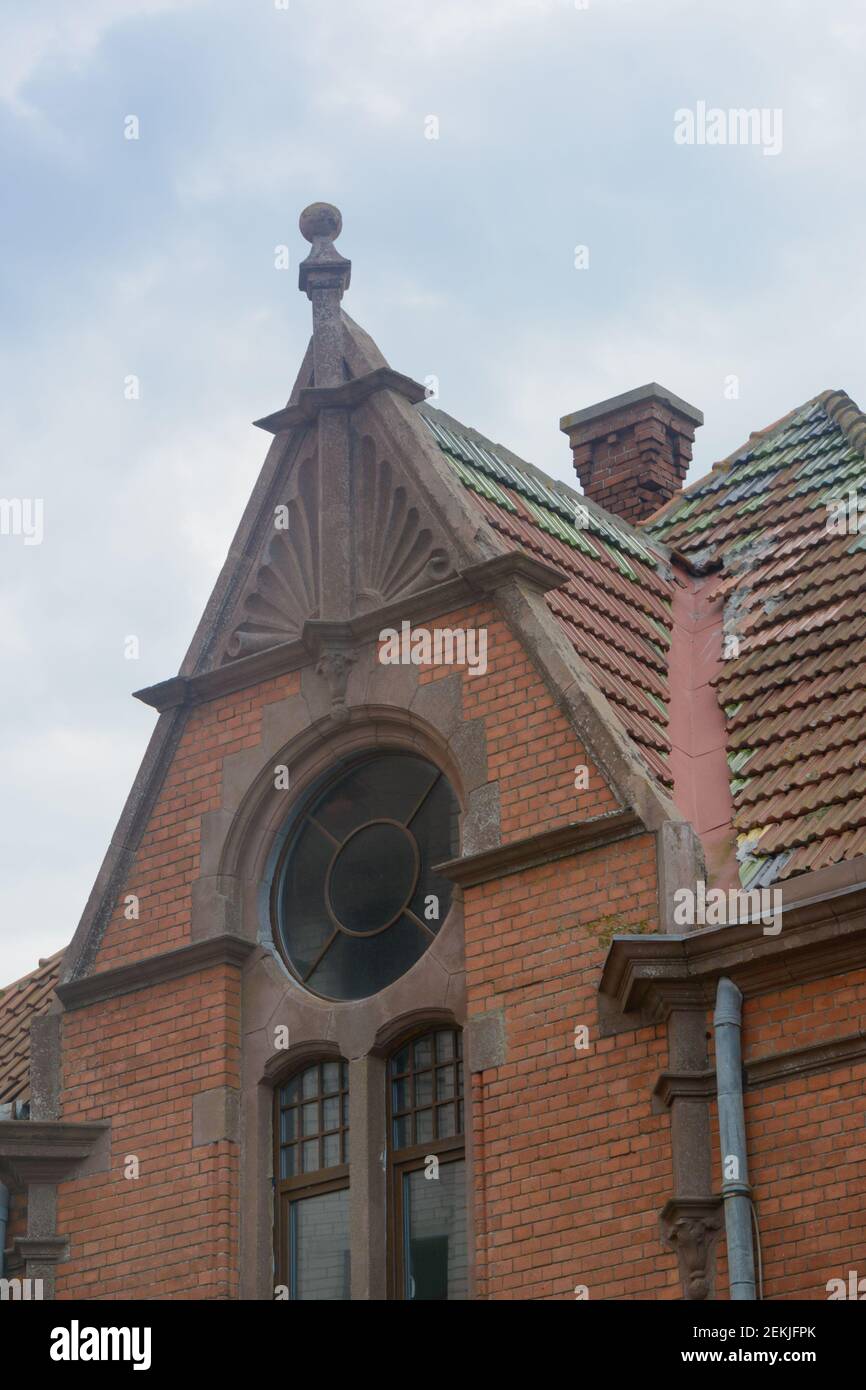 Facade of roof old house in Zelenogradsk. Round window in attic. German ...
