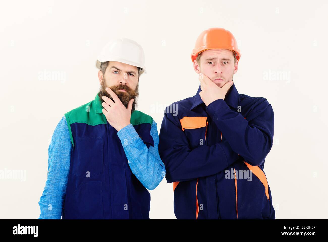 Pensive young men builders, engineers in hard hat, helmet standing and ...