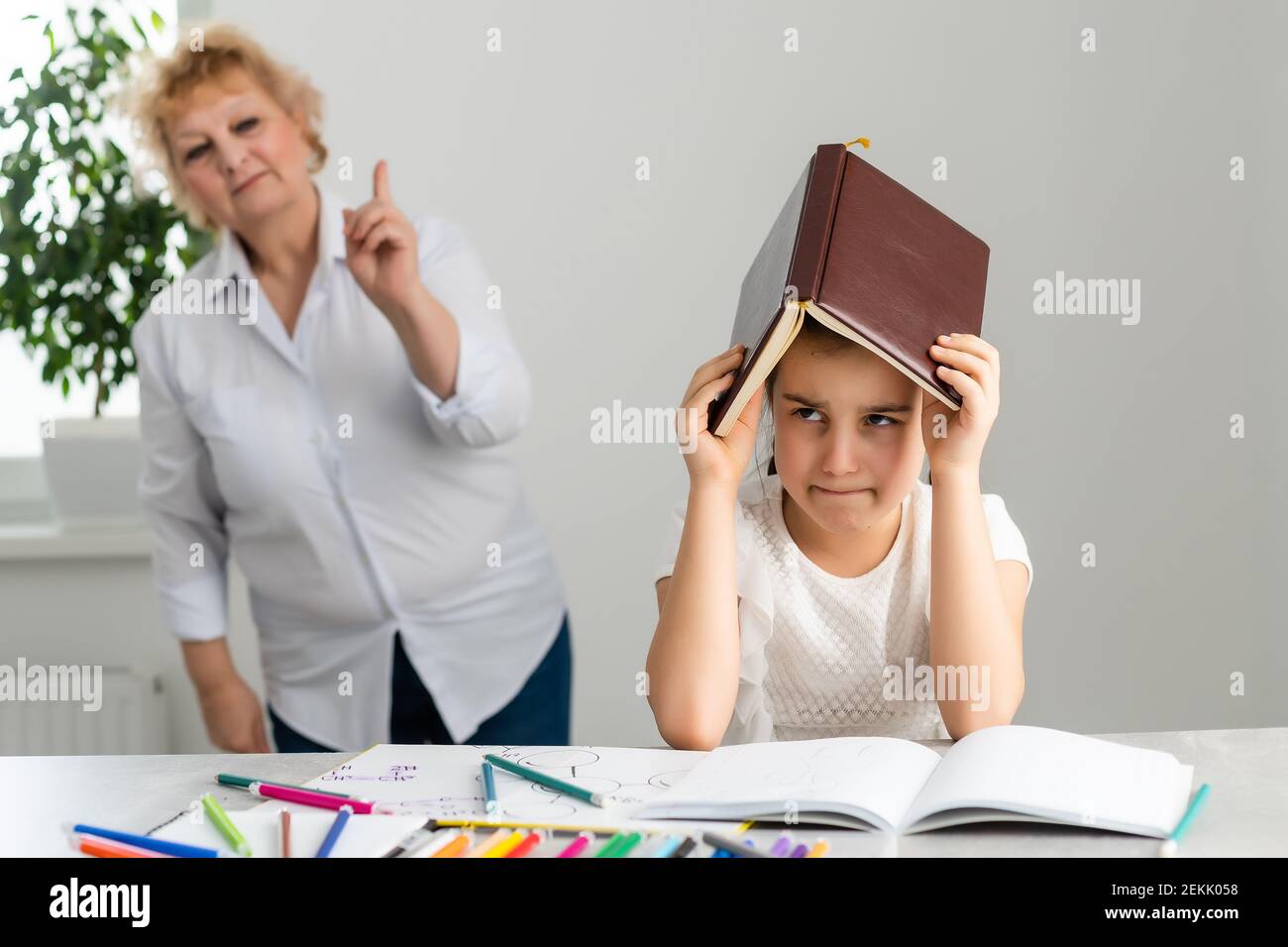 Woman tutor or foster parent mum helping cute caucasian school child ...