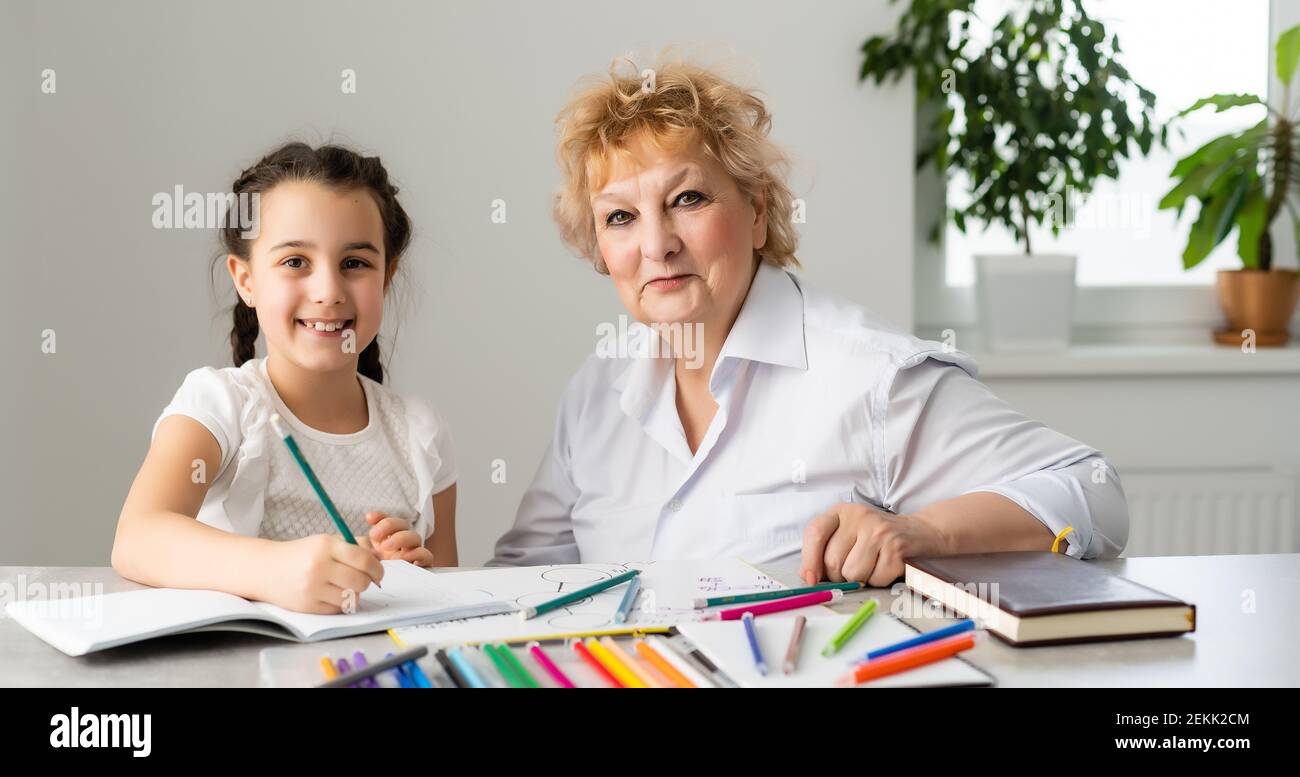 Woman tutor or foster parent mum helping cute caucasian school child ...