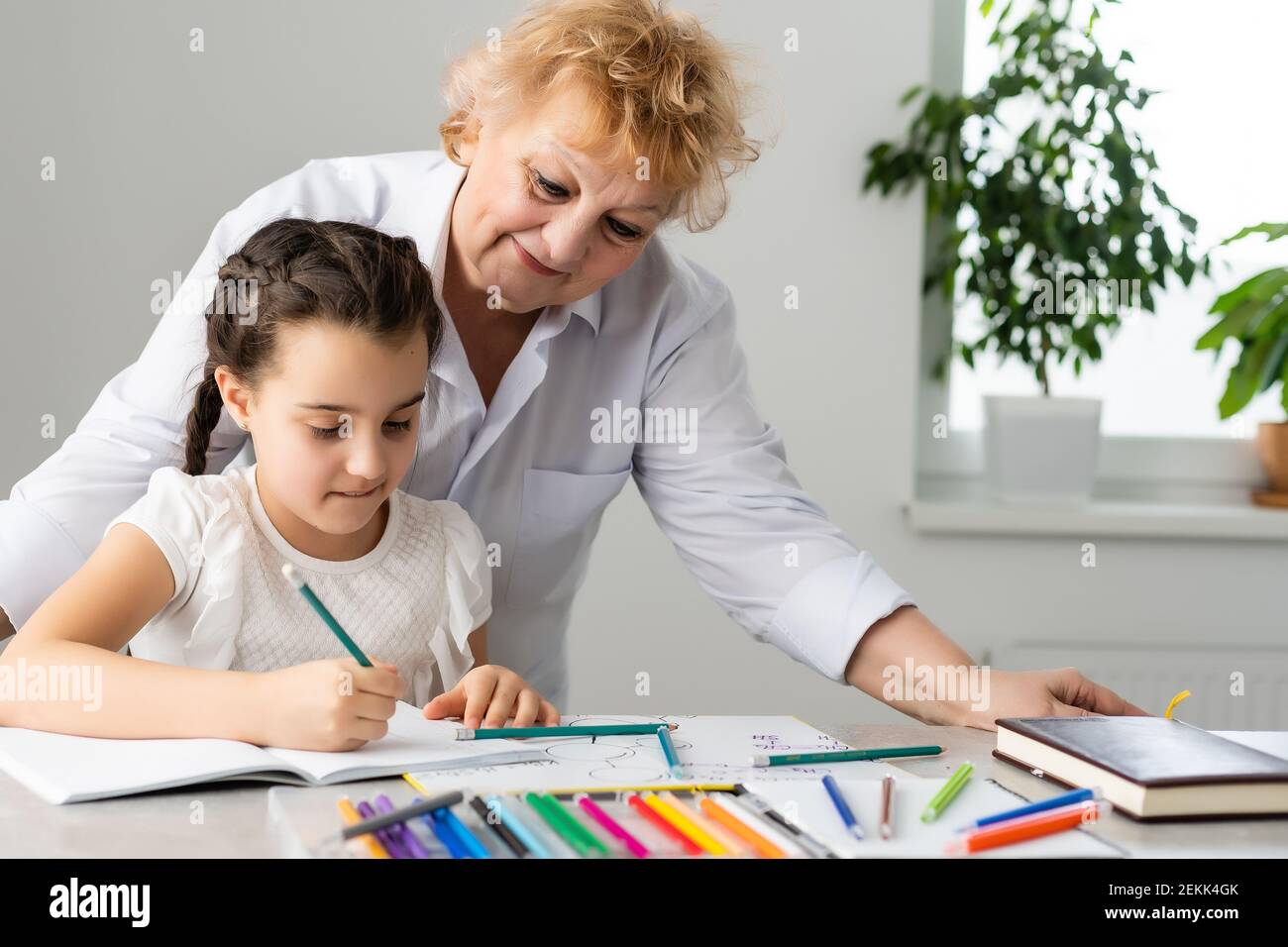 Woman tutor or foster parent mum helping cute caucasian school child ...