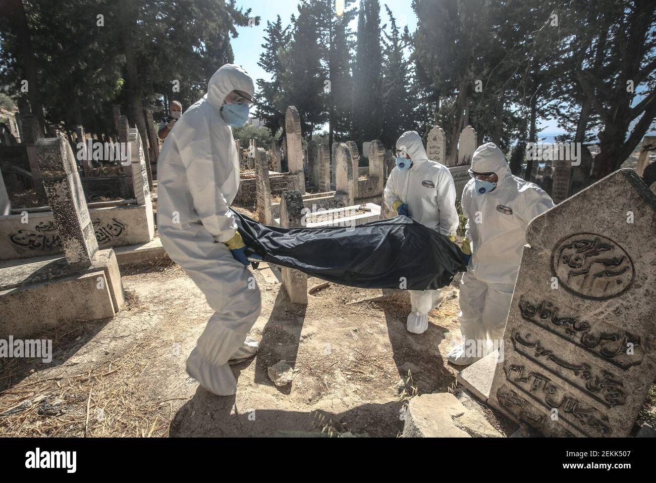 Gravediggers working wearing personal protective equipment (PPE) during ...