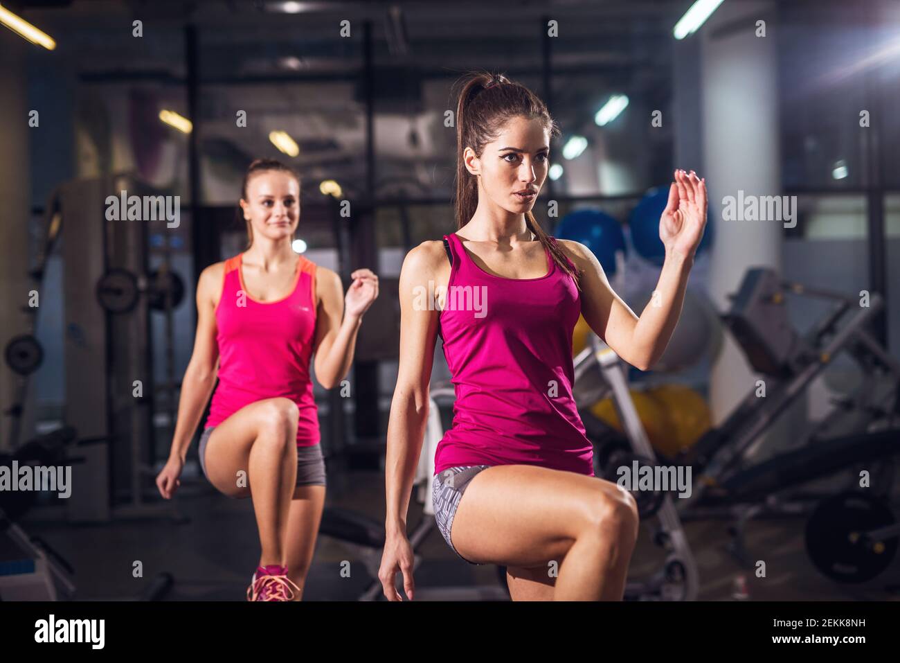 Two young energy athletic slim fitness active girls lifting legs while ...