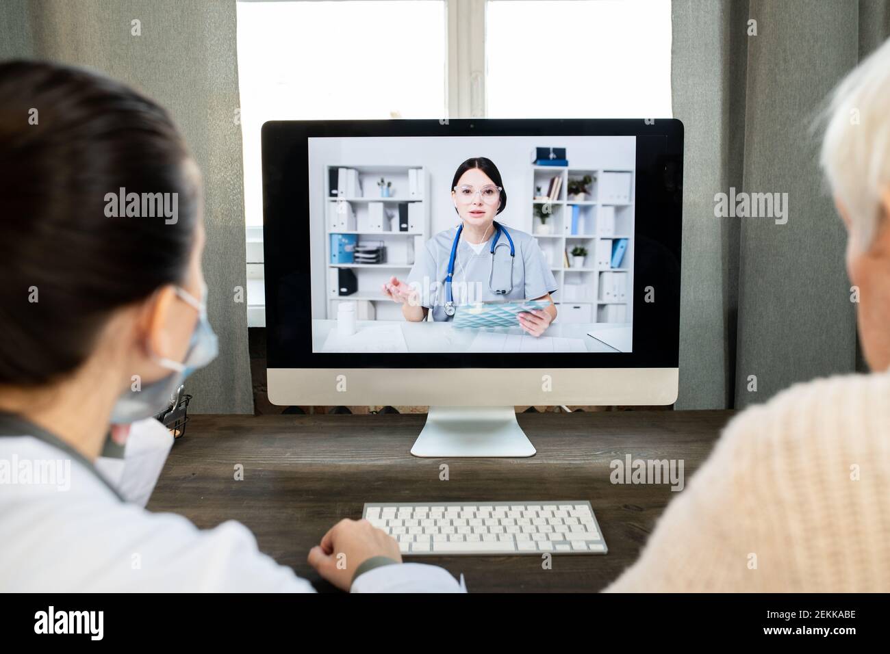 Senior man and general practitioner sitting by table in front of ...