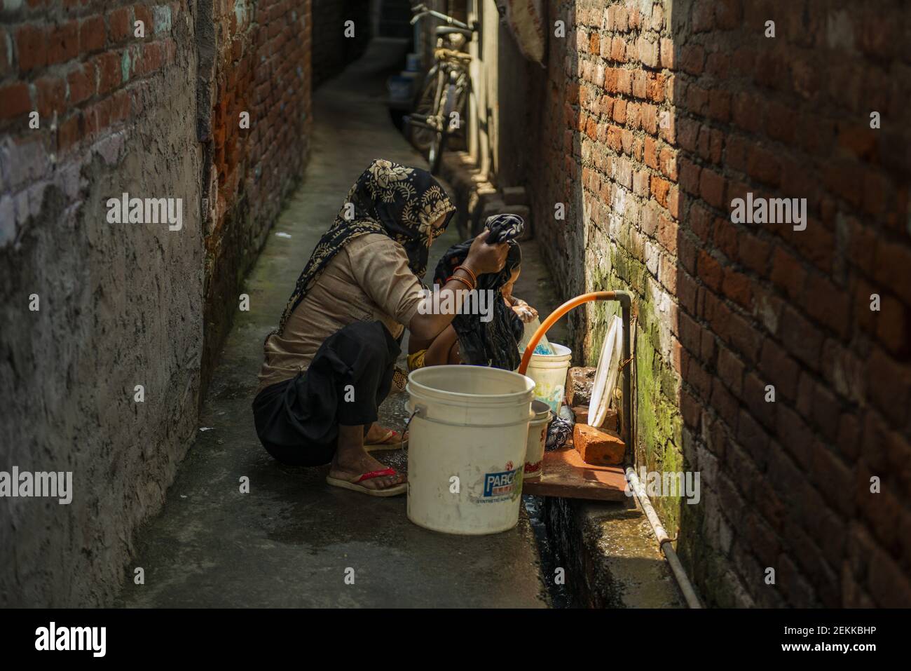Woman washing her clothes in a narrow lane of the slum cluster. Anna ...