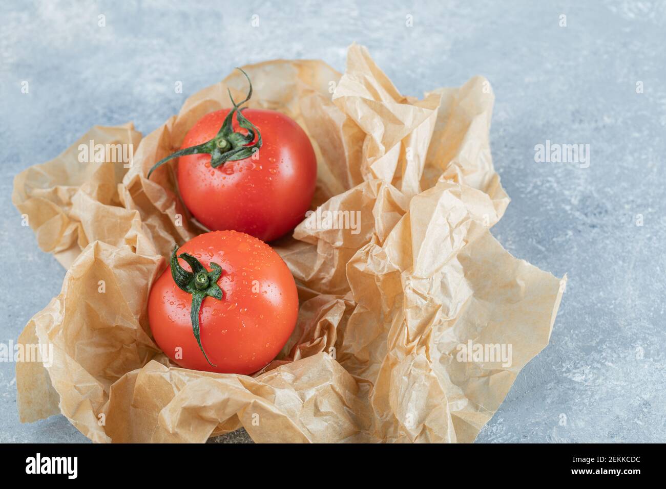 Two fresh whole tomatoes on a parchment paper Stock Photo - Alamy