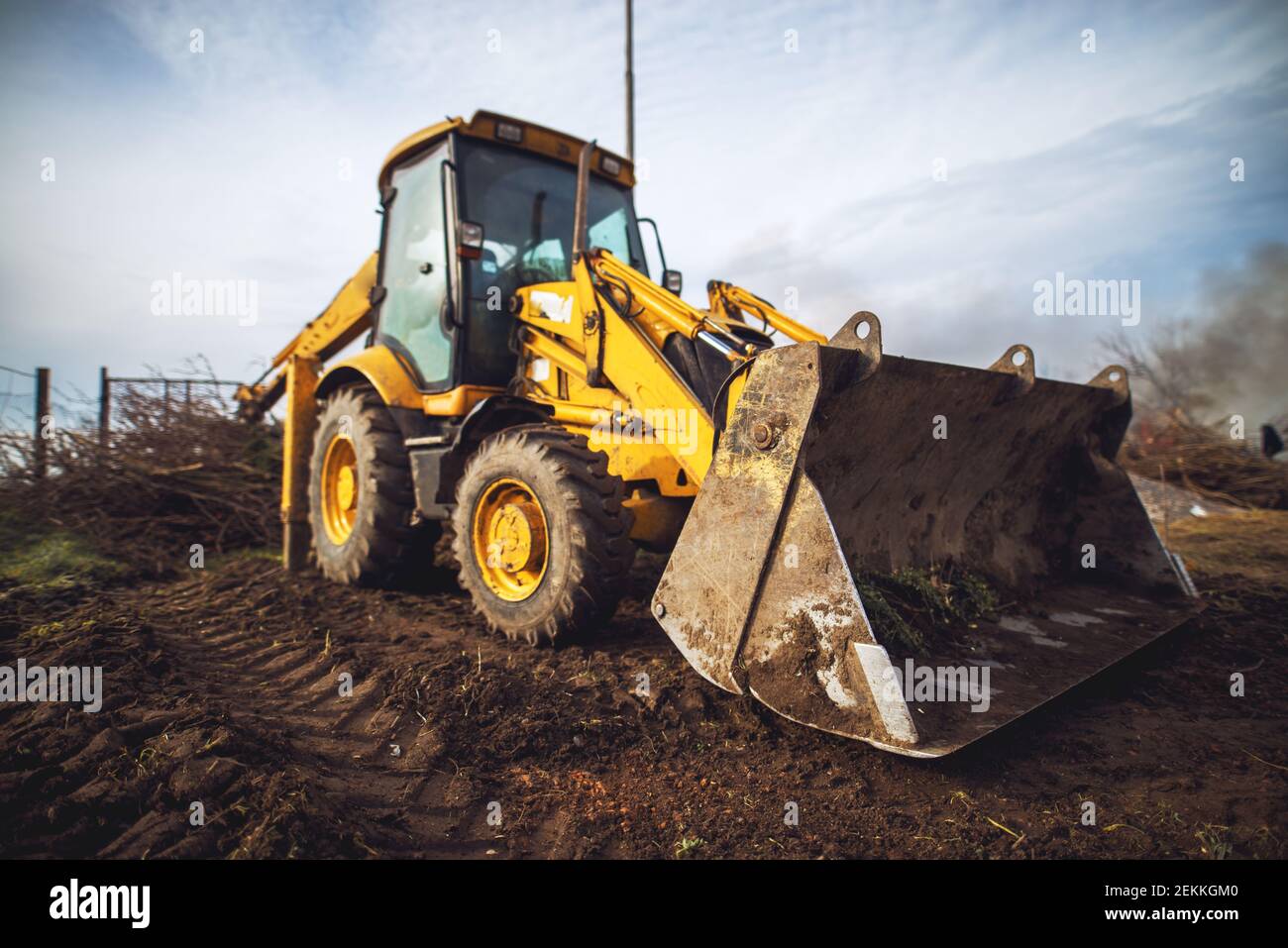 Yellow excavator while cleaning backyard of industrial space Stock ...
