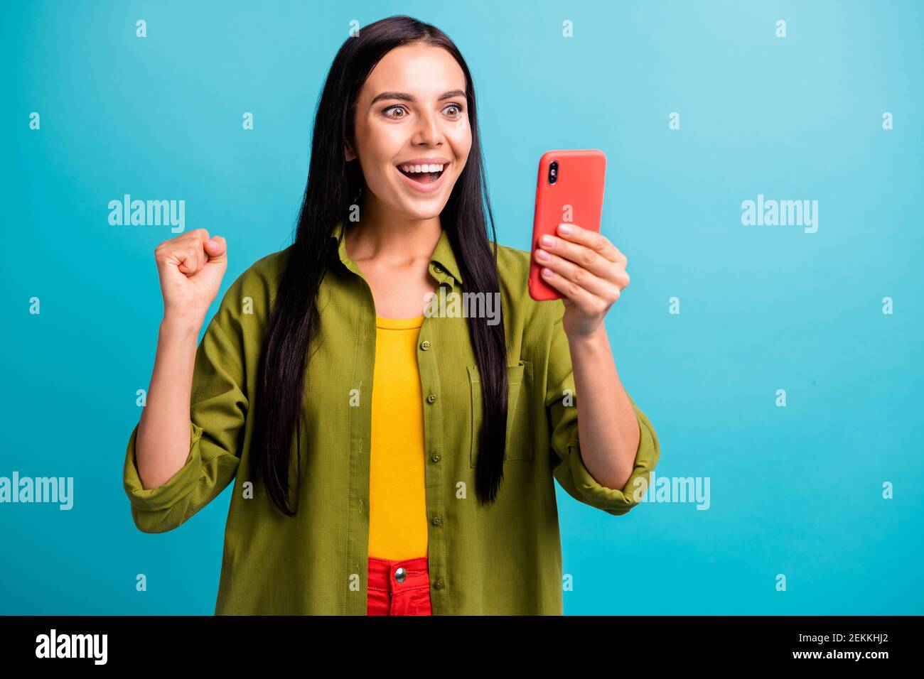 Photo of amazed girl hold phone raise fist open mouth look screen wear ...