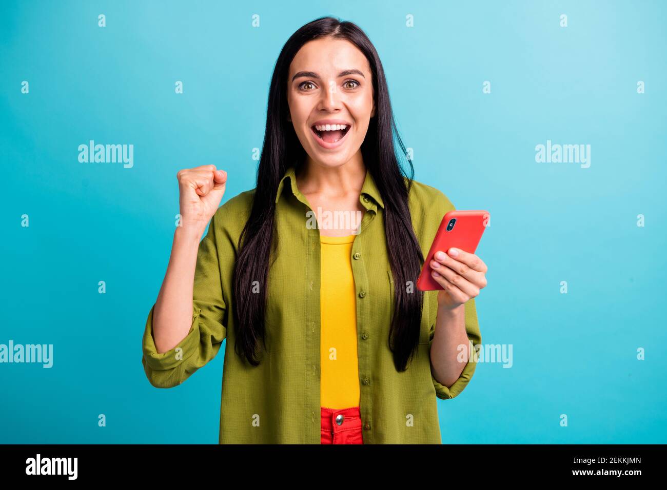 Photo of cheerful excited girl hold phone raise fist open mouth wear ...