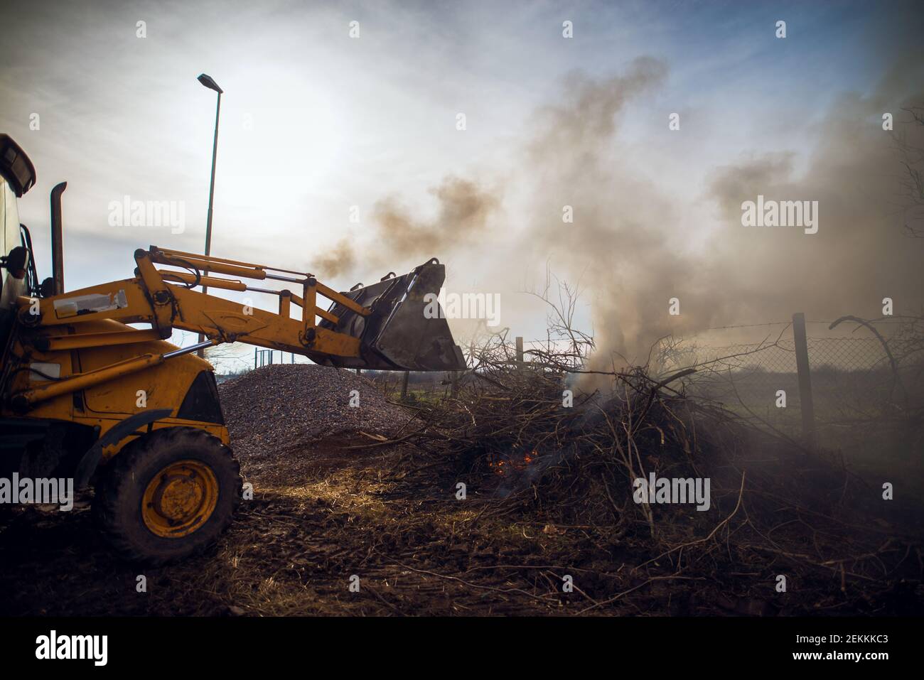 Yellow bagger cleaning backyard of industrial space while putting woods ...