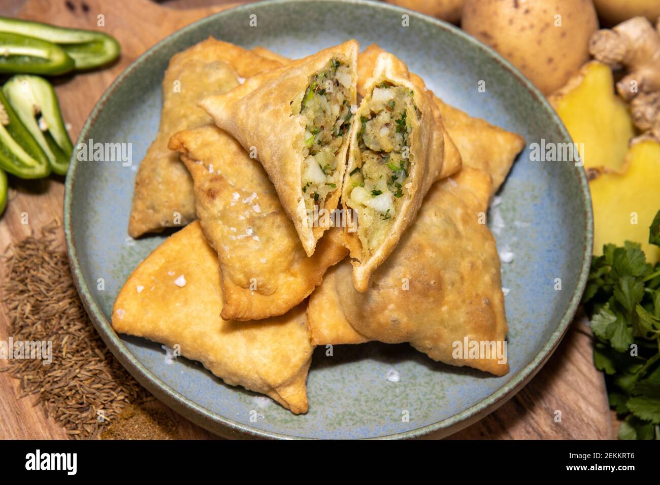 A delicious pile of vegetable Indian samosas on a wooden kitchen table ...