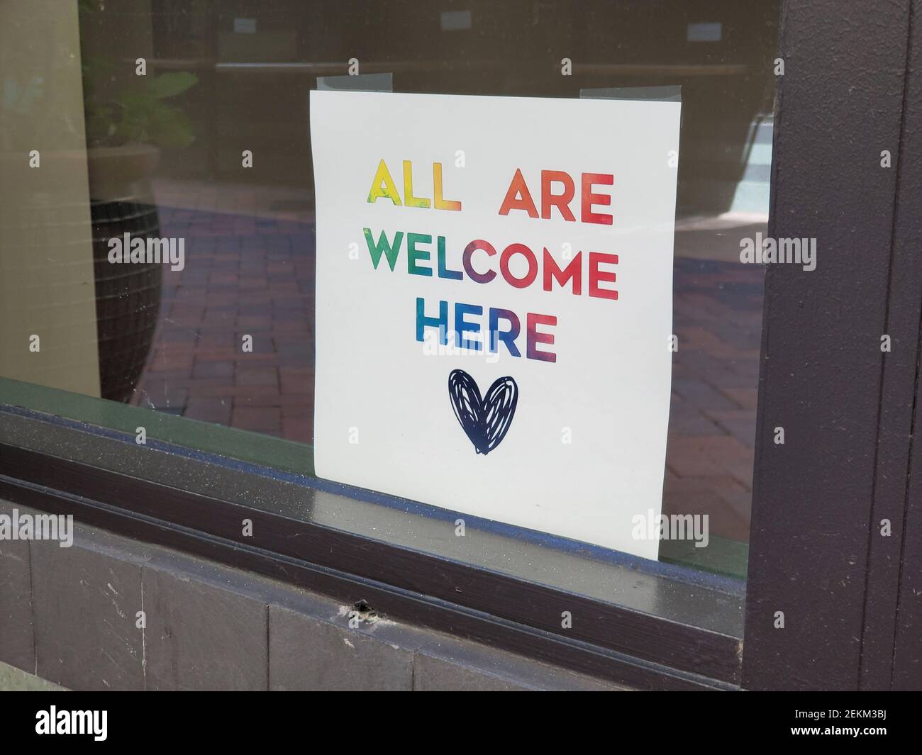 A sign with a message of inclusion and a rainbow color motif is visible ...