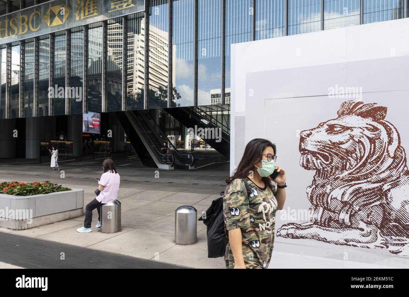 Pedestrians wearing masks walk past the British multinational banking ...