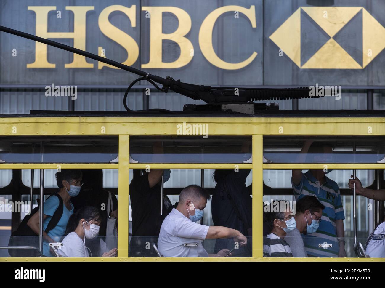 Commuters wearing masks ride on a tram as it passes by the British ...