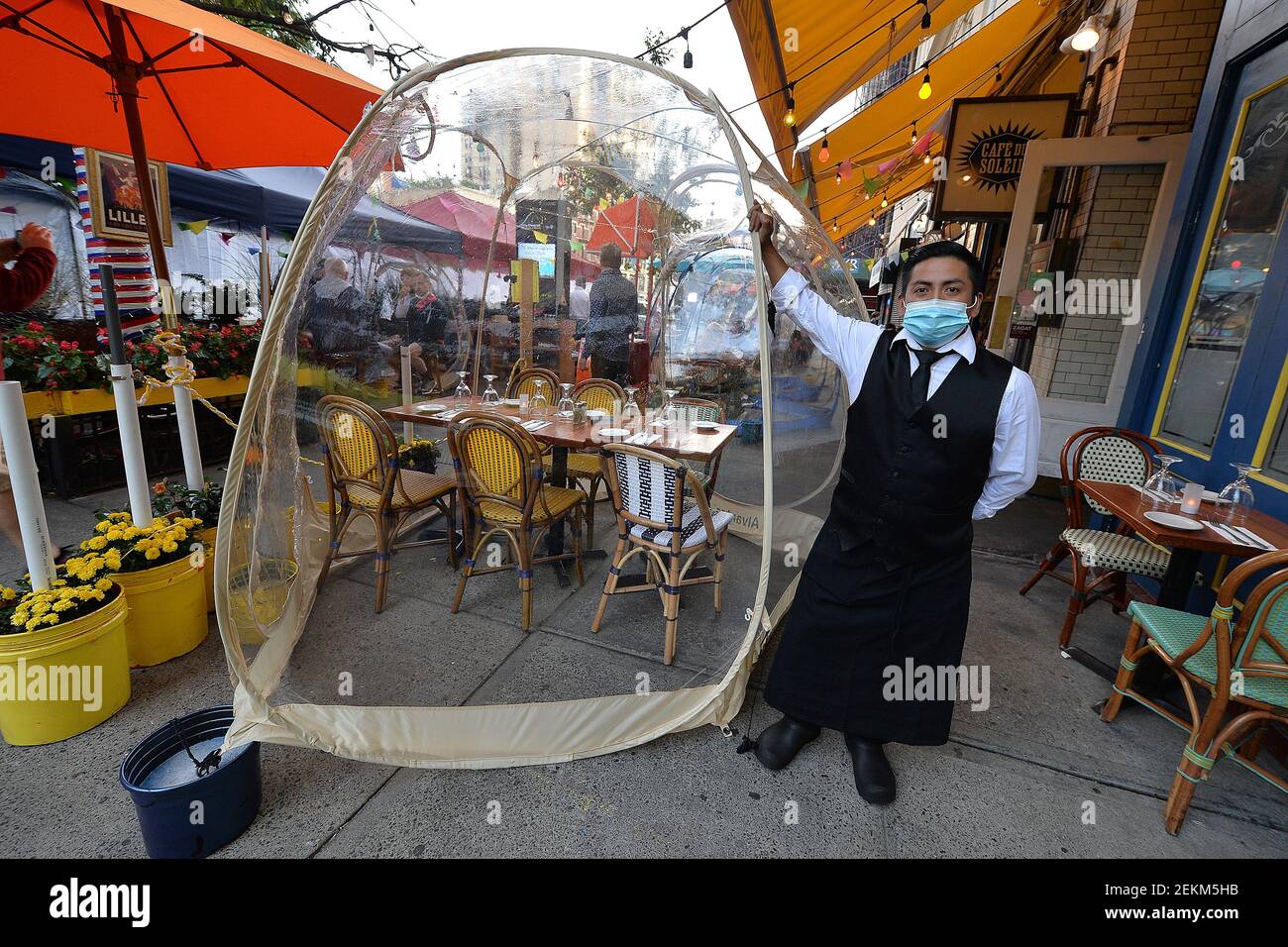 A food runner stands next to a plastic “space bubble” pop-up tent where ...
