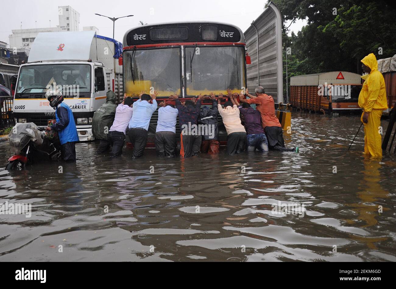 People push a public transport bus on a waterlogged road. Heavy rains ...