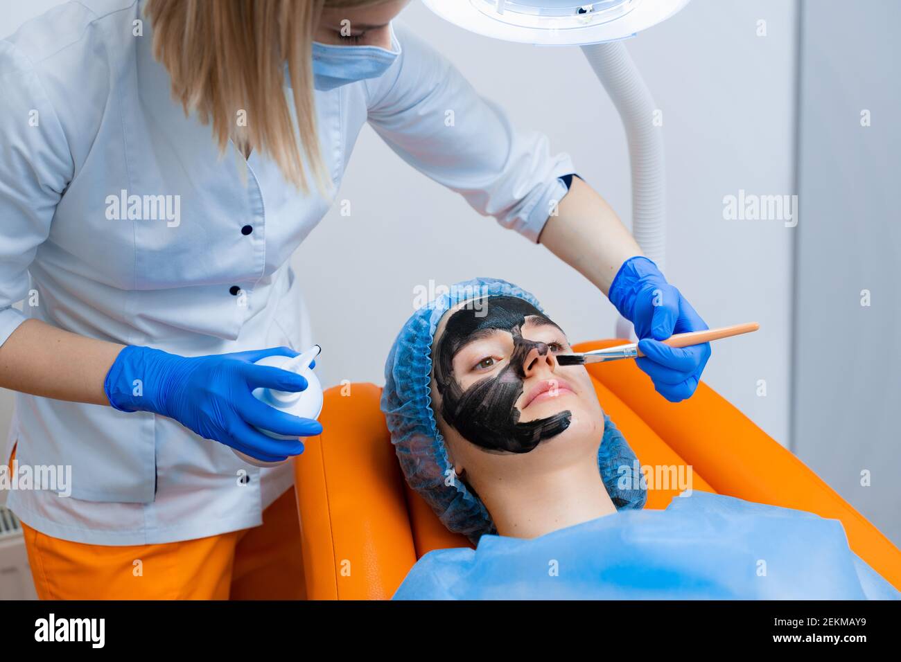 Dermatologist smears black mask on face for laser photorejuvenation and ...