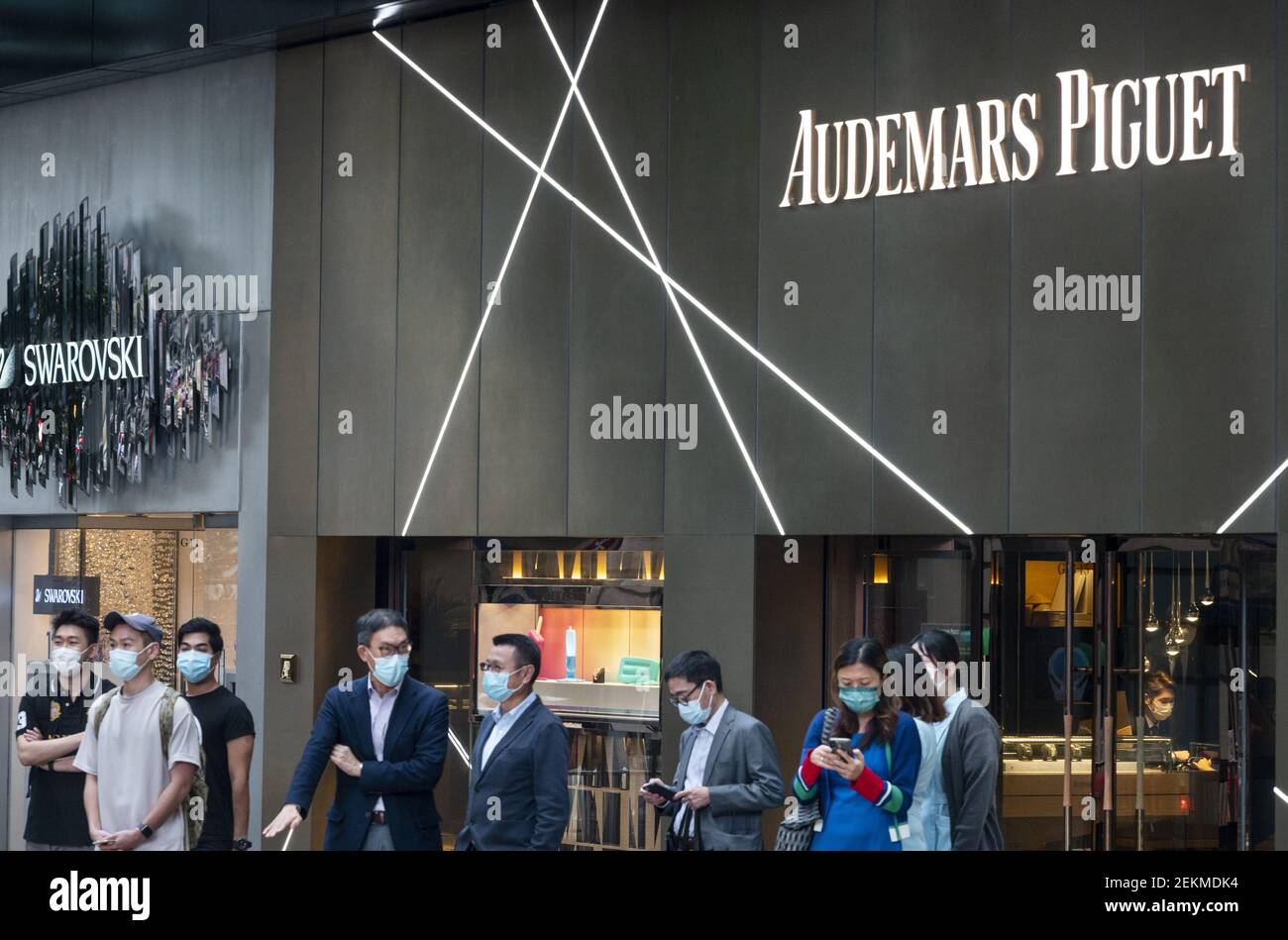 Pedestrians wearing masks are seen at a street traffic light in front ...