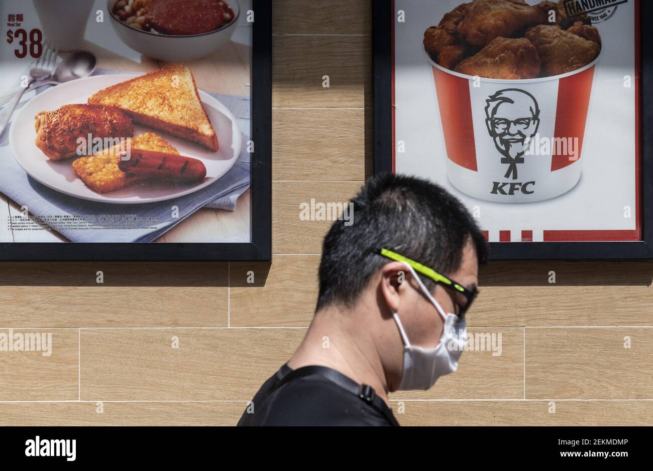 A pedestrian wearing a face mask walks past American fast food chicken ...