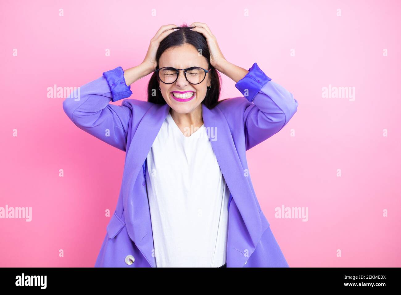 Young business woman wearing purple jacket over pink background ...