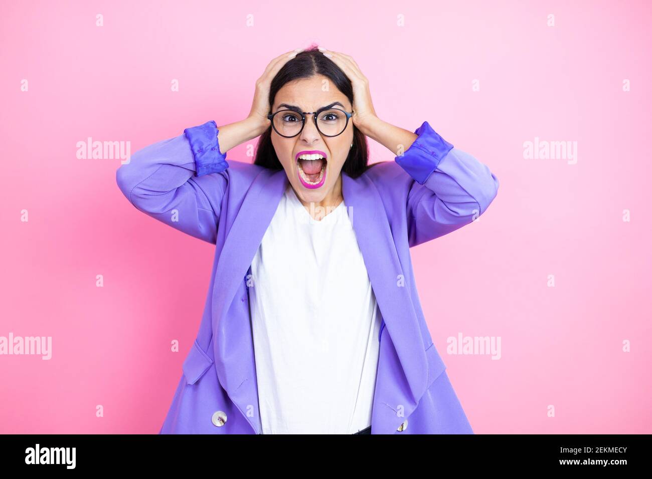 Young business woman wearing purple jacket over pink background crazy ...