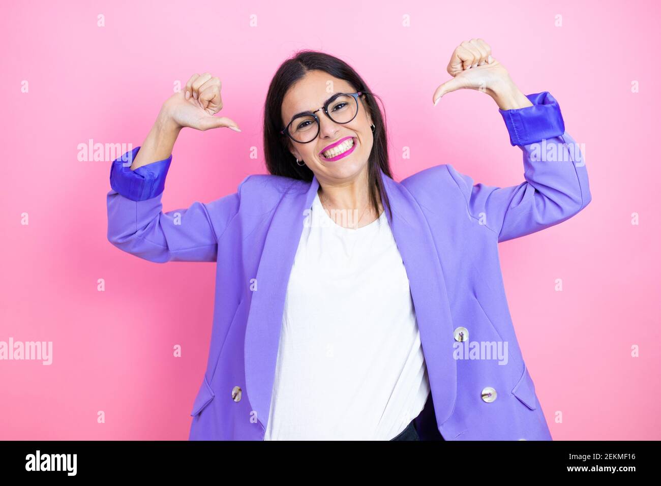 Young business woman wearing purple jacket over pink background looking ...
