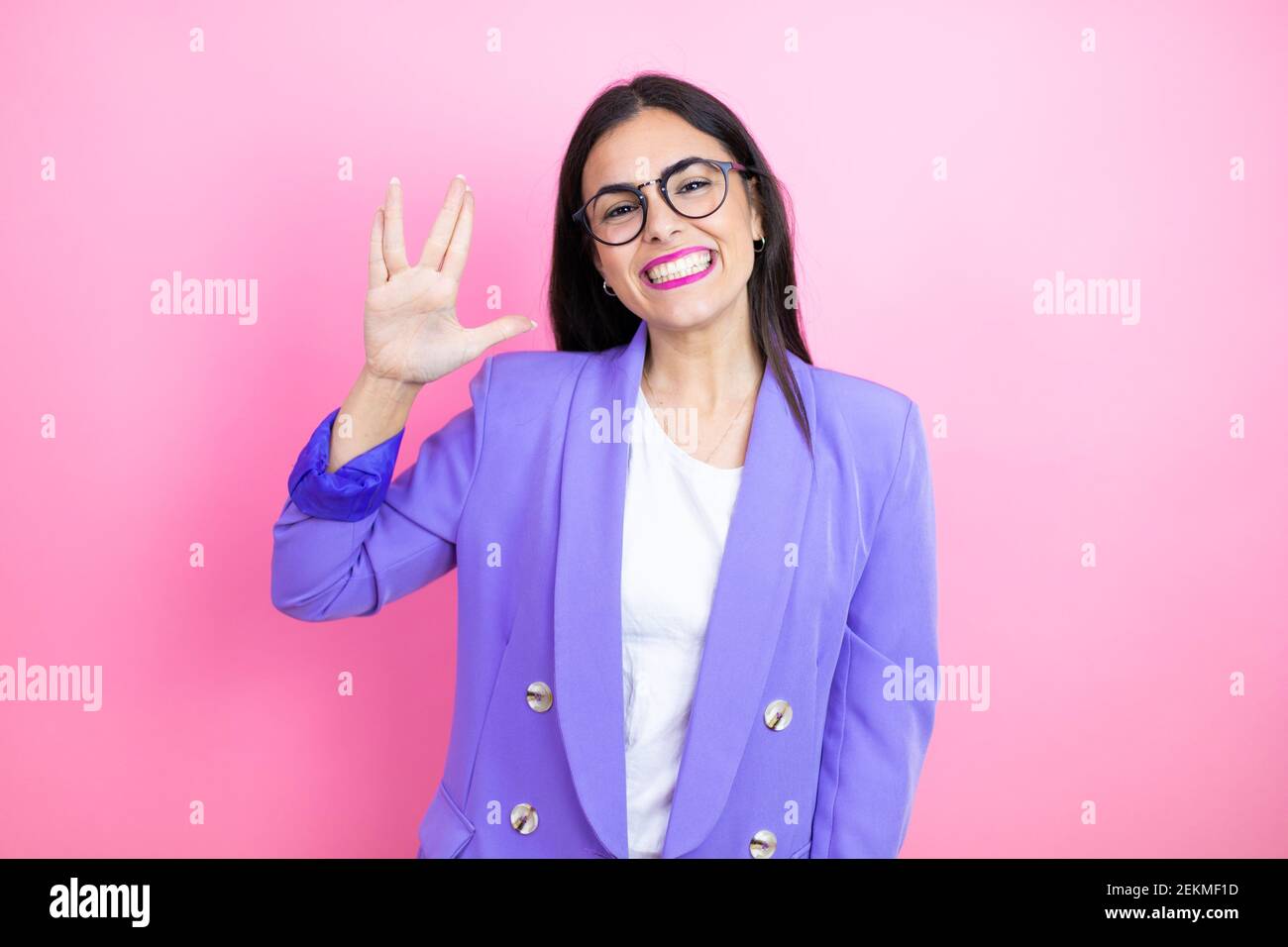 Young business woman wearing purple jacket over pink background doing ...