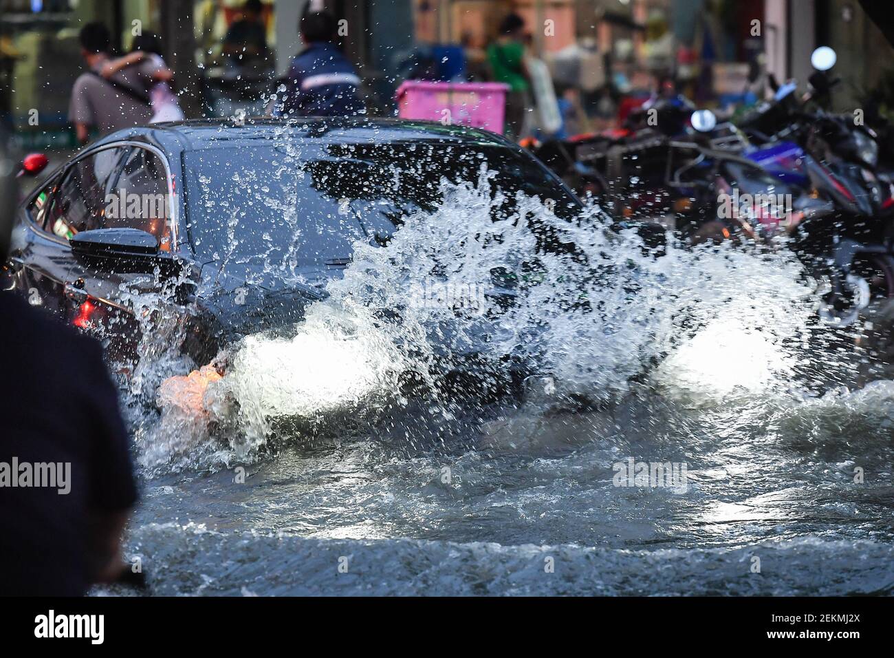 A vehicle seen splashing water as it moves on a waterlogged street ...