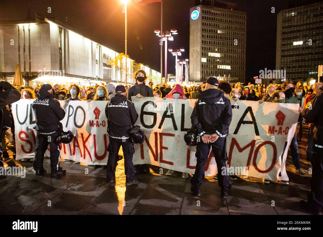 Protesters holding a banner face a police line in front of the ...