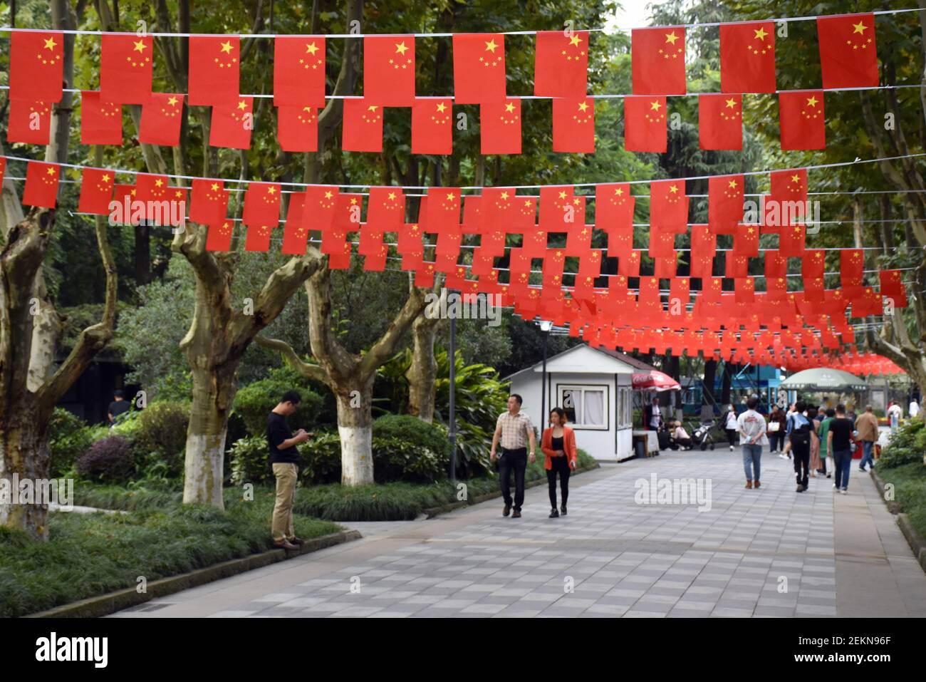 National flags fly on the street, under which vehicles and pedestrians ...
