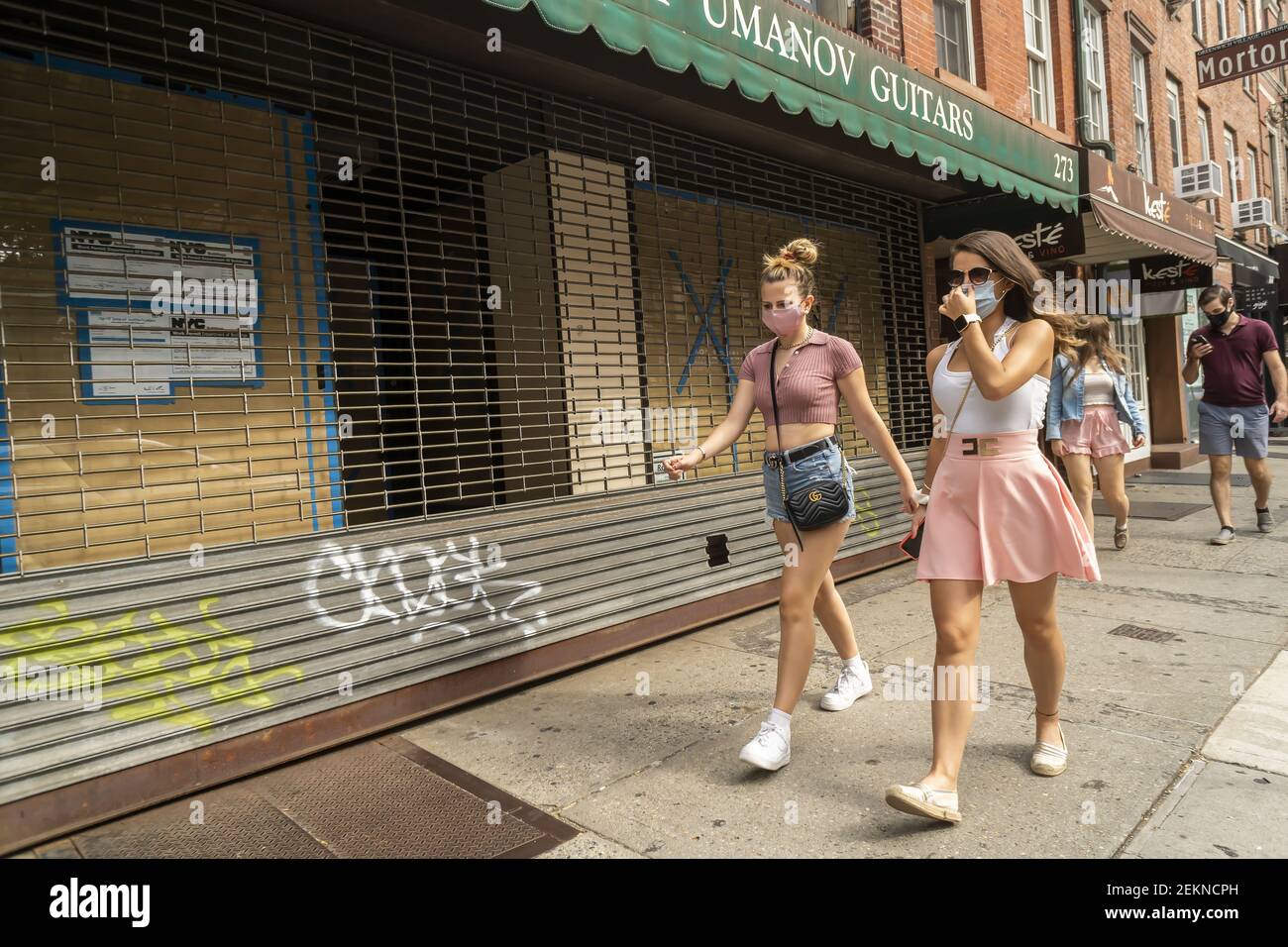 Women walk passed closed storefront on trendy Bleecker Street in the ...