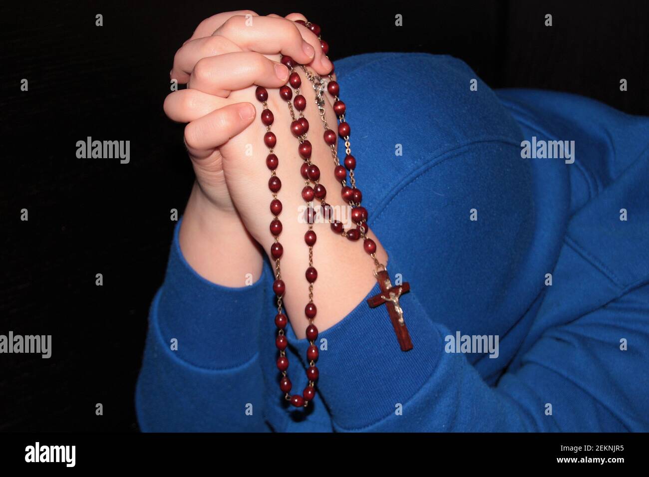 Child praying and holding the cross on his hands Stock Photo - Alamy