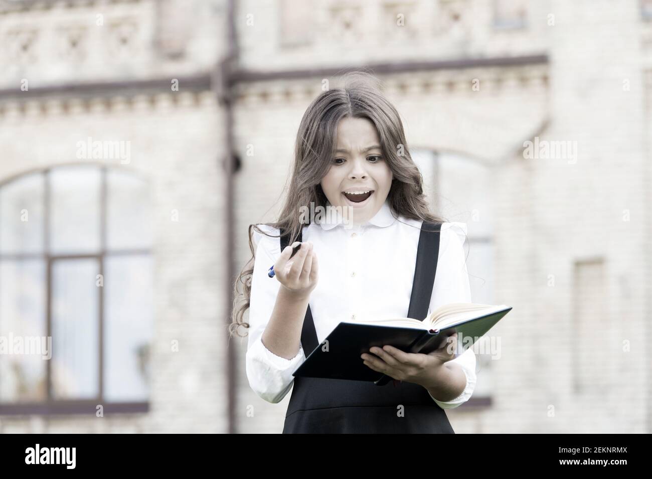 Keep writing. Happy little girl with textbook and writing pen outdoor ...