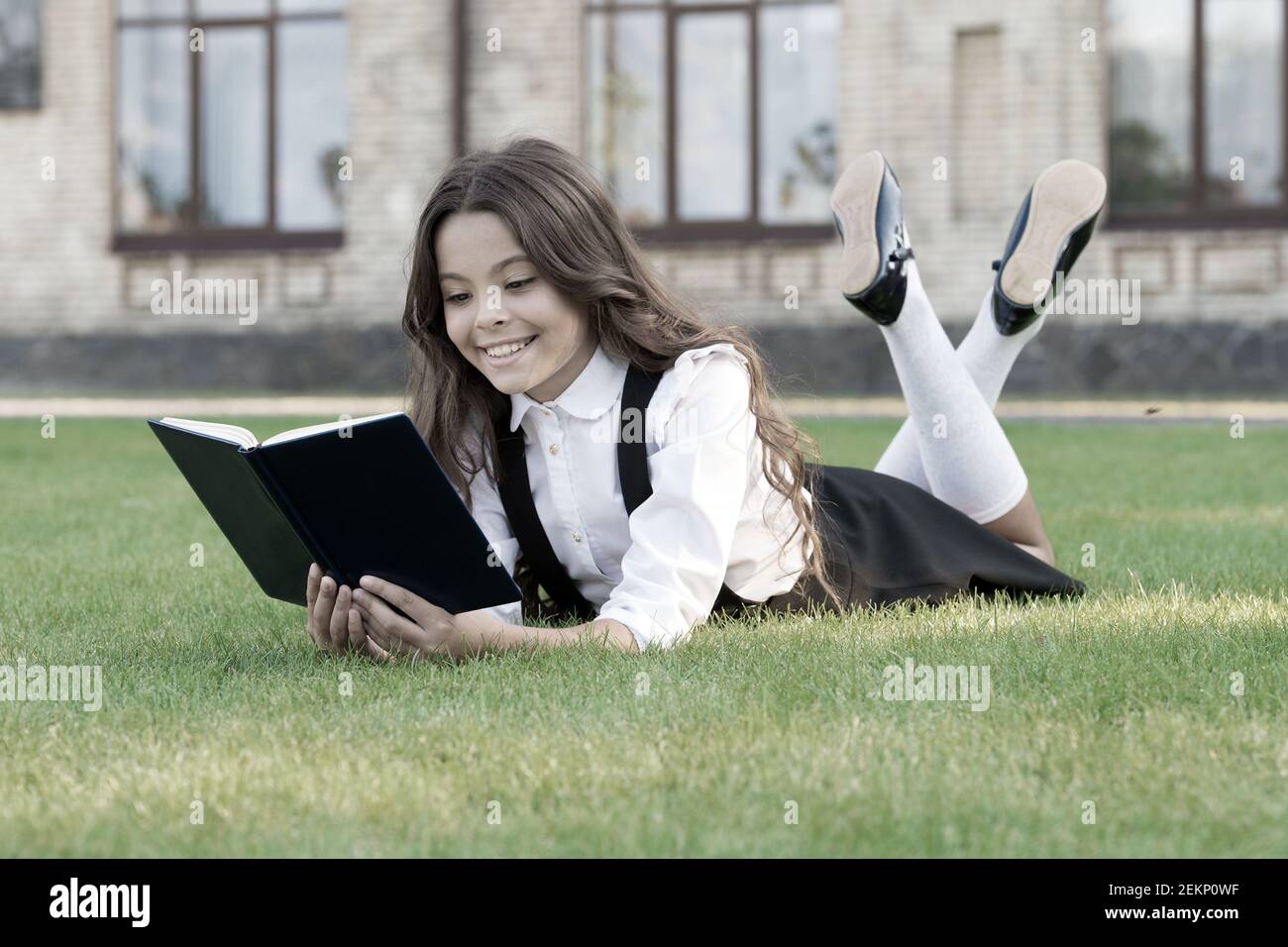 Lesson on fresh air. Cute small child reading book outdoors. Schoolgirl ...