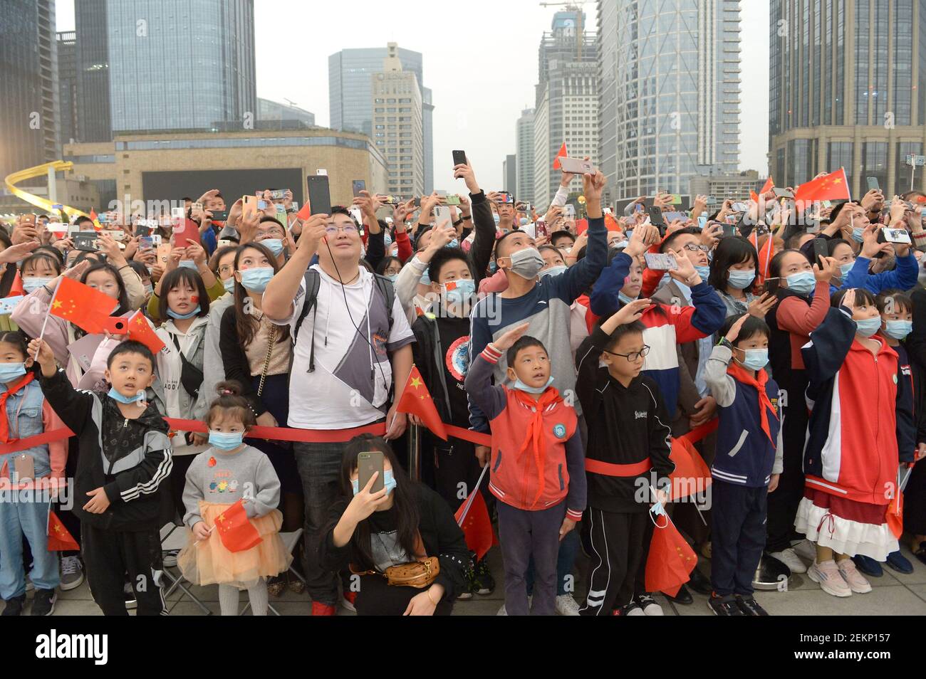 People wave Chinese flags while watching the Chinese flag raising ...