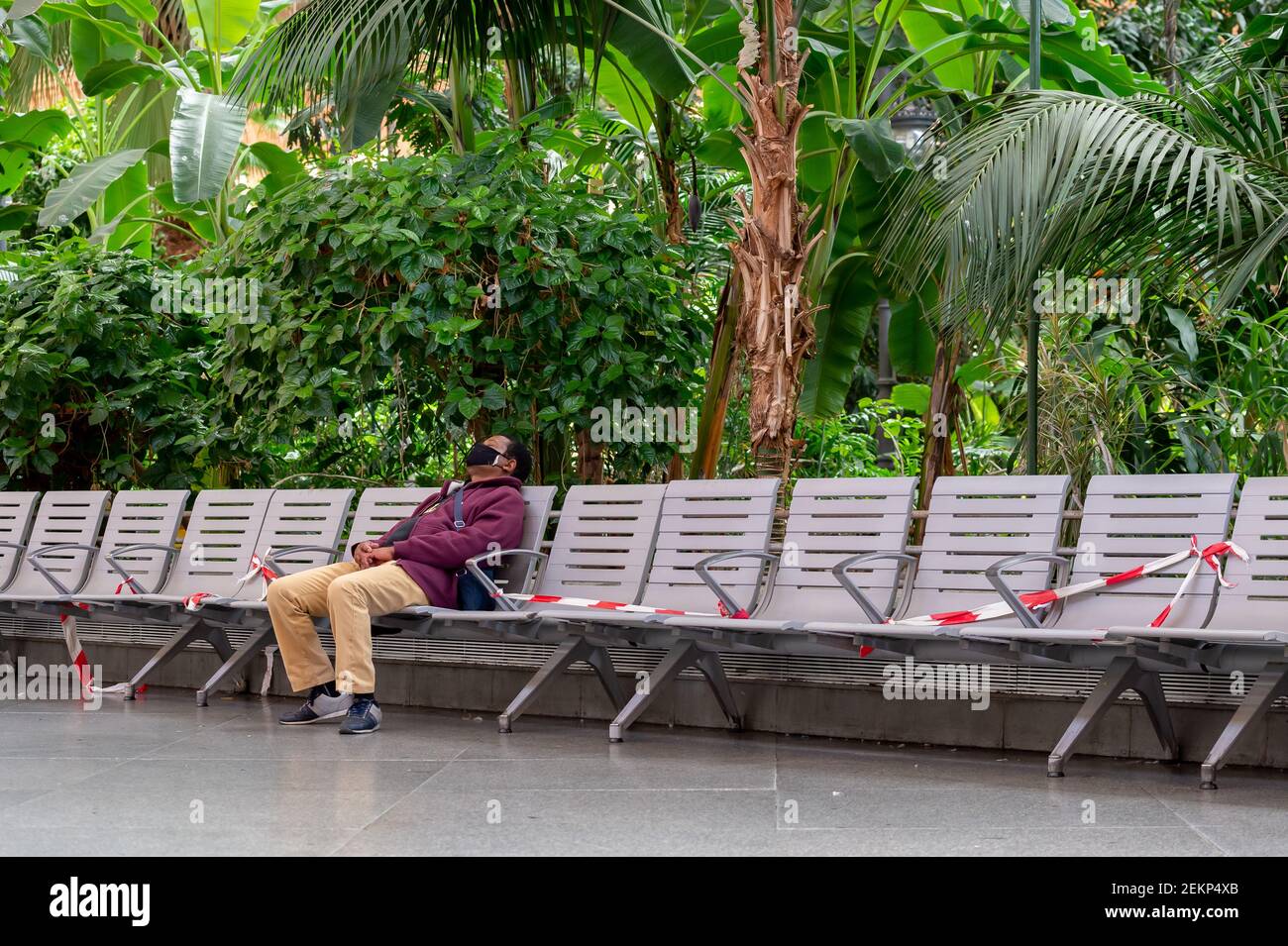 A man resting on the chairs of the Atocha main train station. Today is ...